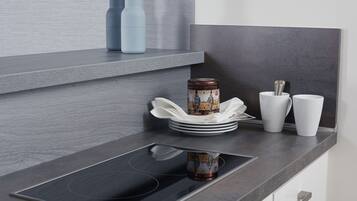 Cozinha moderna com cooktop por indução embutido, armários cinza e coifa de aço inoxidável.