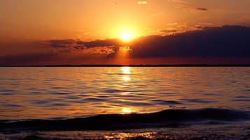 Um pôr do sol sobre um mar calmo, com horizonte nítido.