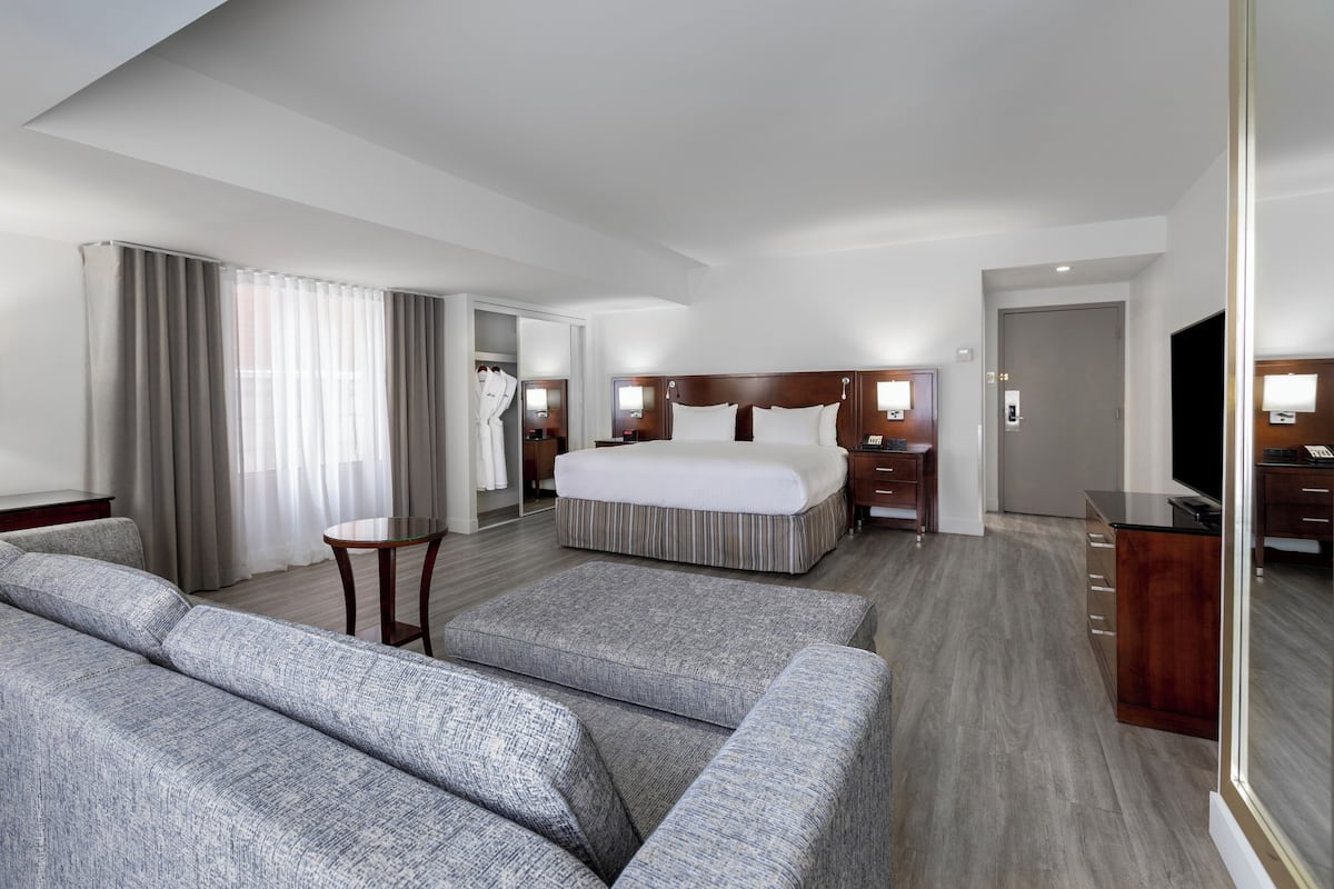 Quarto de hotel com uma cama grande, um sofá, uma escrivaninha e uma televisão.