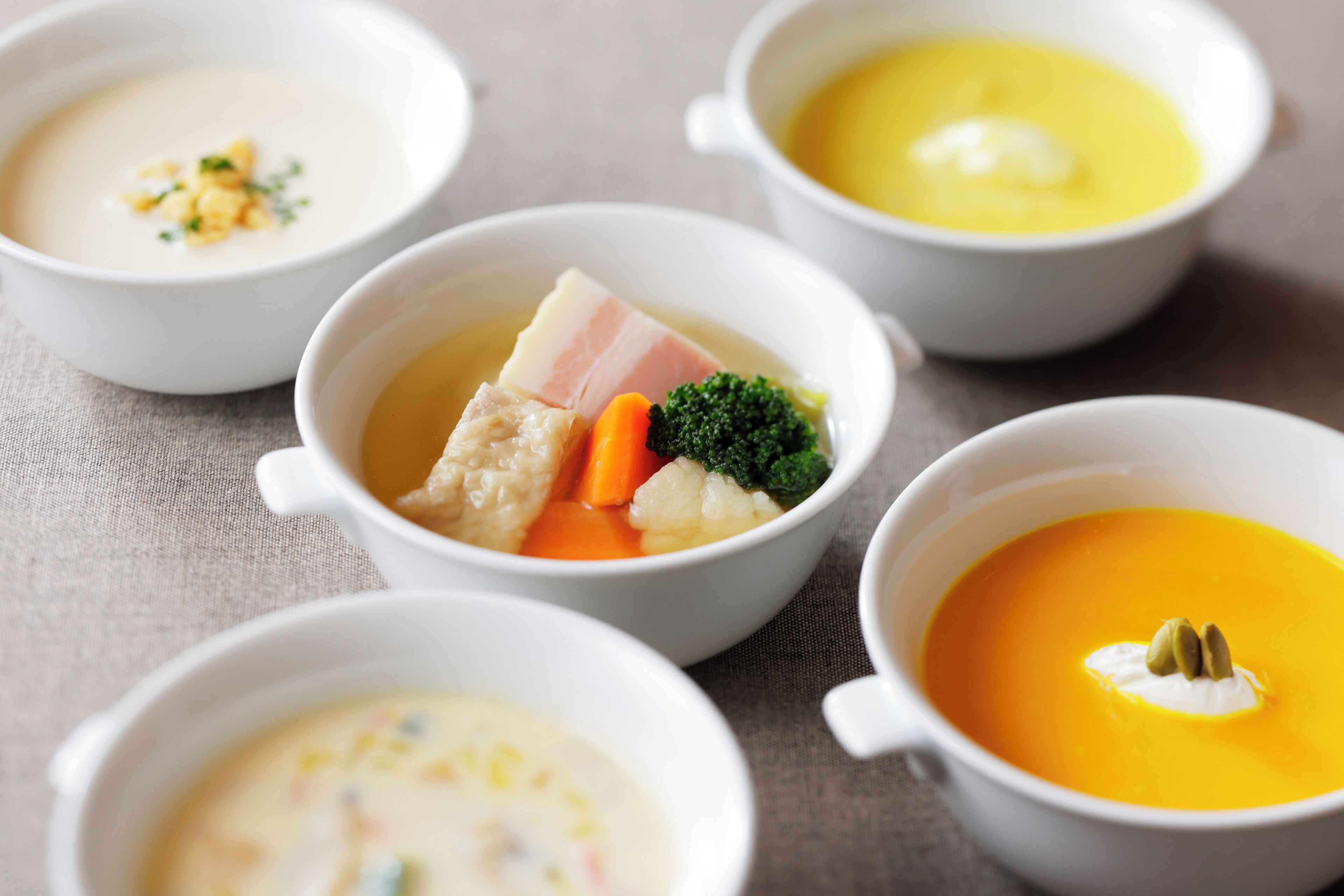 Quatro tigelas de sopa com diferentes ingredientes.