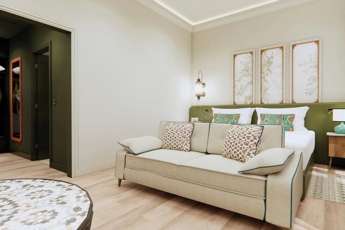 Quarto moderno com cabeceira verde, sofá bege e mesa de centro redonda.
