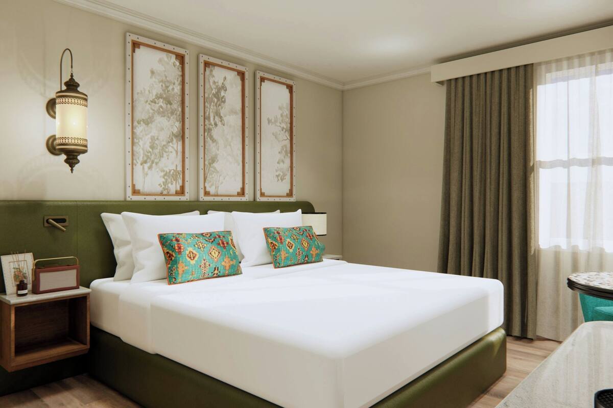 Uma cama bem arrumada com lençóis brancos e almofadas decorativas, uma mesa de cabeceira com abajur e quadros nas paredes.
