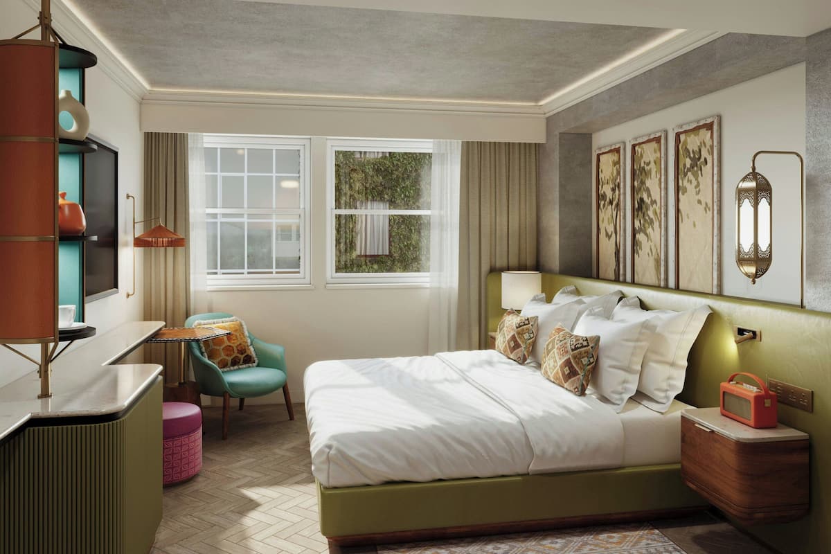 Quarto com cama, mesa de cabeceira, luminária, cadeira e janela com cortinas.