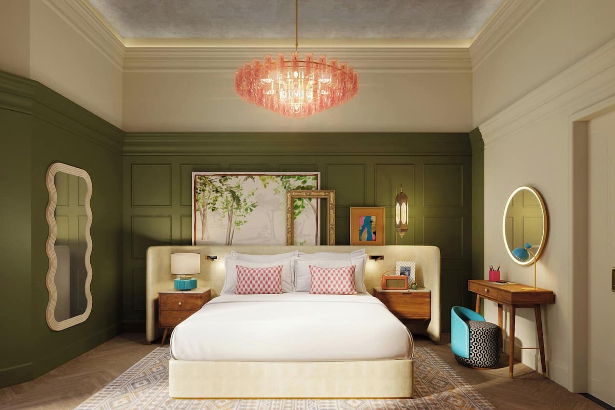 Quarto com cama grande, lustre, espelho e cômoda.