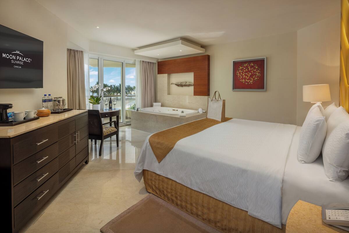 Quarto de hotel com cama, escrivaninha, televisão, banheiro e vista para o exterior.