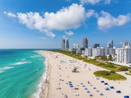 Na praia, praia de areia branca, espreguiçadeiras, guarda-sóis de praia 