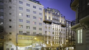 Um hotel com vários andares, uma estrutura de cúpula de vidro imponente, várias varandas e fachada bem iluminada.