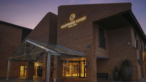 Um edifício de tijolos com entrada de vidro e uma placa que diz "HAMPSTEAD COURT HOTEL 3-4-5A".