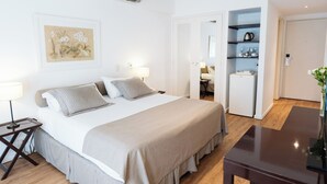 Quarto com cama, mesas de cabeceira, escrivaninha e guarda-roupa.
