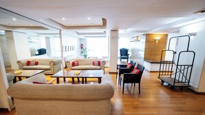 Um hall de hotel moderno com sofás, área de refeições e um carrinho.
