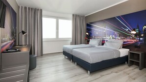 Quarto de hotel moderno com uma cama grande, uma escrivaninha e um mural com vista para a cidade.