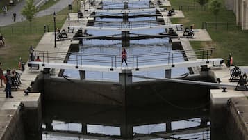 Sistema de cadeados com canais de água, uma ponte ao fundo e um horizonte urbano.