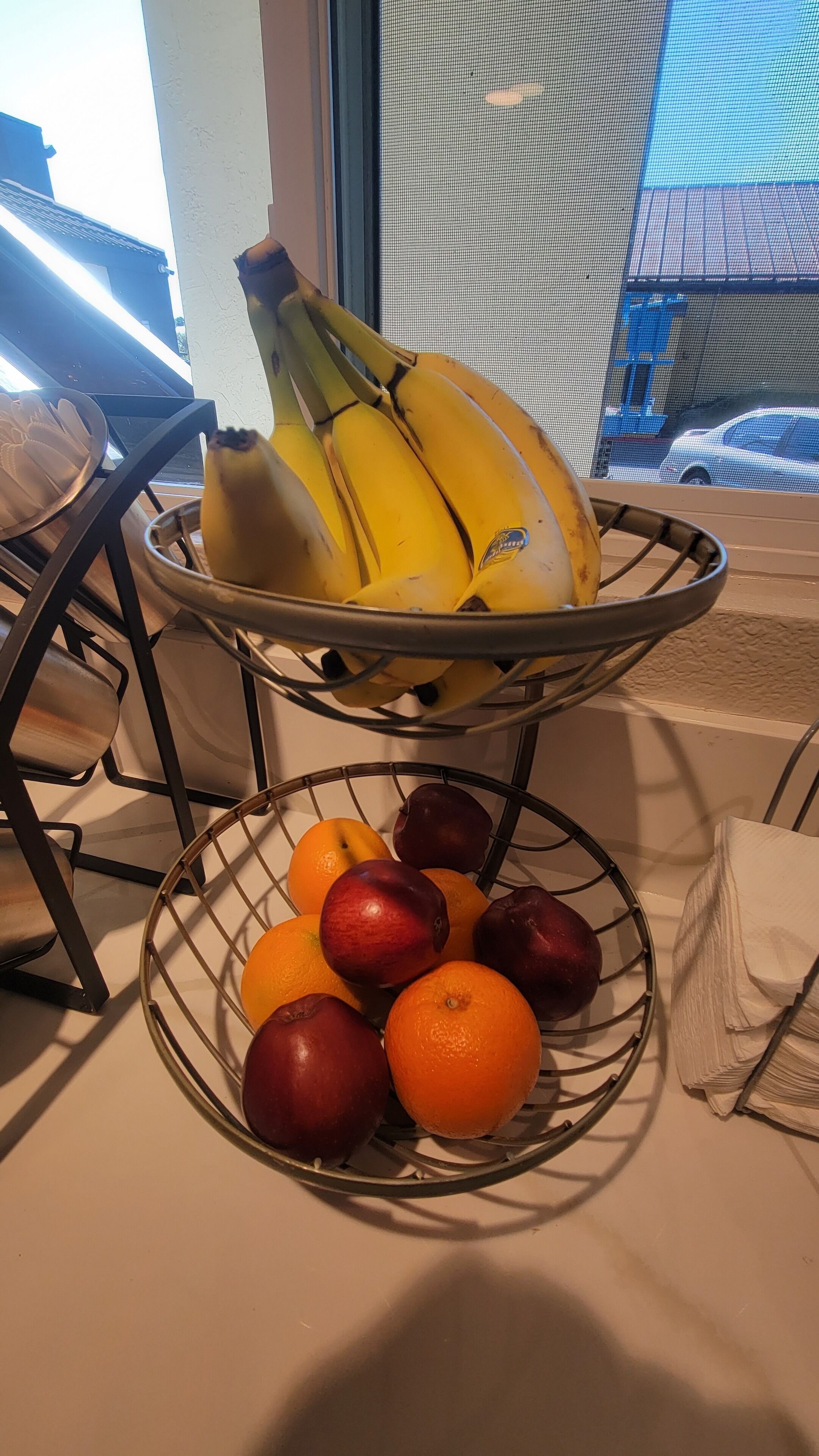 Uma cesta de frutas com bananas e maçãs em uma bancada de cozinha.
