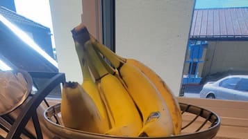 Uma cesta de frutas com bananas e maçãs em uma bancada de cozinha.