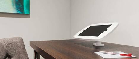 Uma mesa de escritório moderna com um tablet, uma caneta e um pedaço de papel.