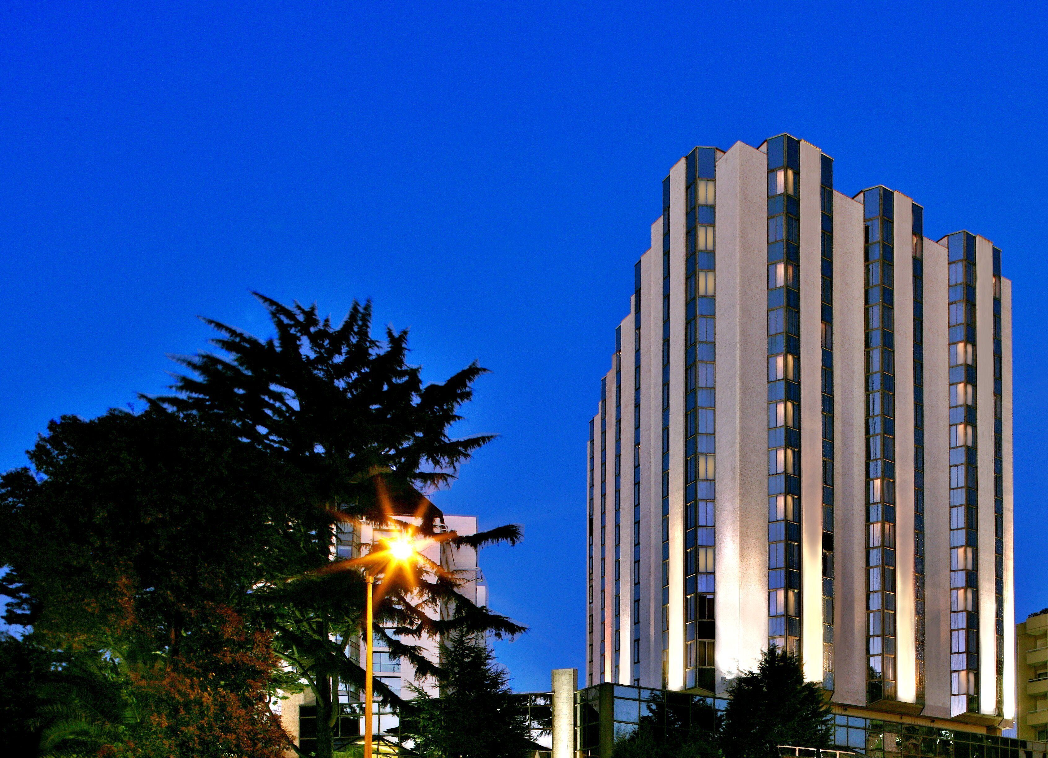 Um edifício alto com design moderno, com uma série de janelas verticais e um telhado plano.