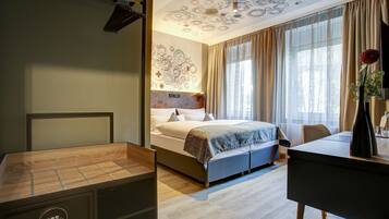 Quarto de hotel moderno com cama, escrivaninha e uma grande janela com cortinas.
