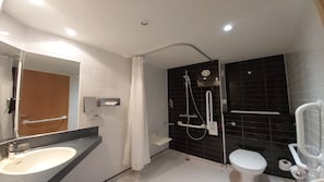 Um banheiro moderno com pia branca, vaso sanitário, chuveiro com chuveiro manual e porta-toalhas.