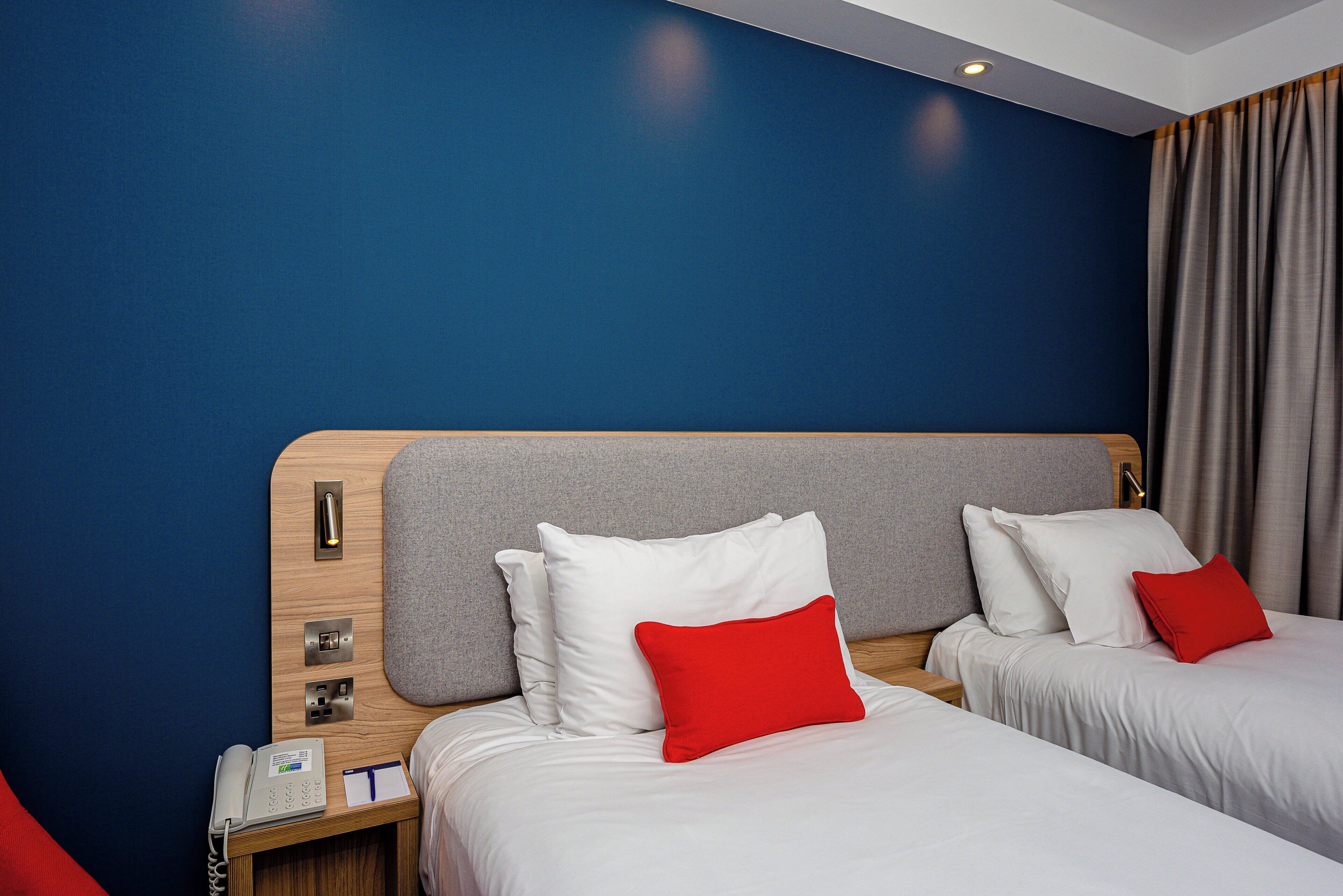 Quarto de hotel com duas camas, telefone ao lado da cama e mesa de cabeceira.