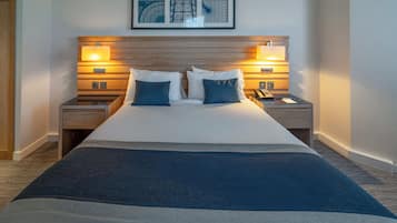 Quarto de hotel com uma cama grande, duas mesas de cabeceira, uma cabeceira e uma obra de arte na parede.