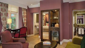 Quarto de hotel com área de estar, uma escrivaninha, um espelho e um banheiro visível através de uma porta aberta.