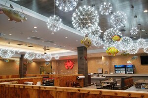 Interior de restaurante com cabines de madeira, balcão e luminárias esféricas penduradas.