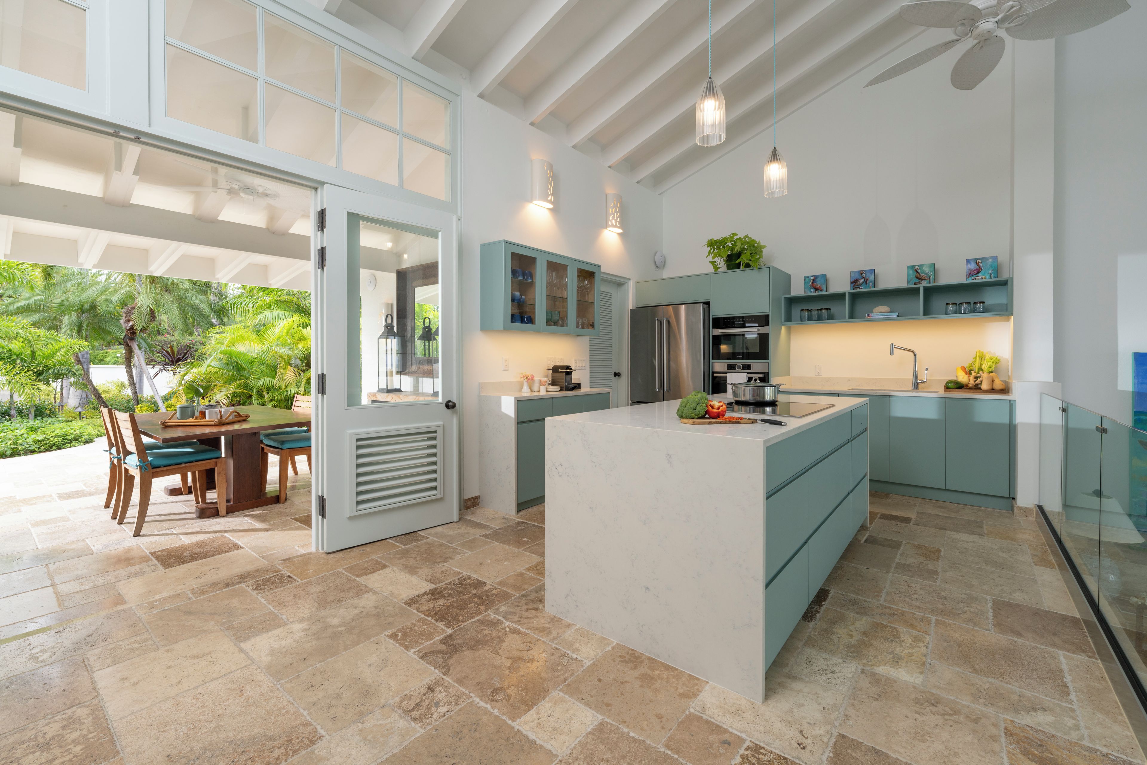 Cozinha moderna com ilha grande, eletrodomésticos embutidos e área de jantar com vista para o exterior.