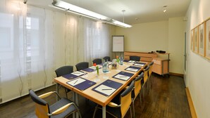 Uma sala de conferências com uma mesa comprida, cadeiras, um projetor e um quadro branco.