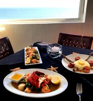 Uma mesa de jantar com dois pratos de mariscos e uma vela.
