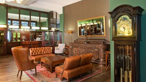 Um hall de entrada com área de bar, mobiliário de couro, um relógio grande e uma parede revestida de azulejos verdes.