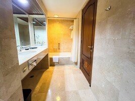 Um banheiro moderno com piso de mármore, um espelho grande, uma banheira e uma porta de madeira.