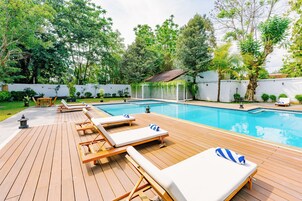 Um deck de madeira com espreguiçadeiras e piscina.
