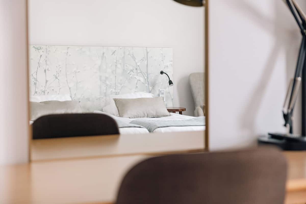 Quarto com cama, mesa de cabeceira, abajur e uma cadeira.