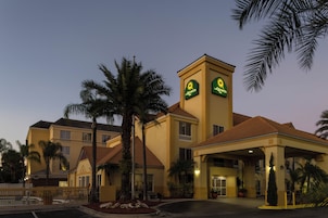 Um hotel com um destaque para o letreiro 'Quinta', uma entrada coberta e uma palmeira em primeiro plano.