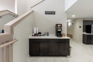 Um café com uma placa acima, uma máquina de café e diversos artigos relacionados a café no balcão.