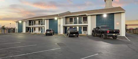 Um motel com estrutura de dois andares, um estacionamento e um caminhão grande estacionado no local.