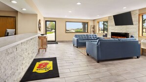 Um lobby moderno com uma receção, dois sofás, lareira e grandes janelas com vista para o exterior.
