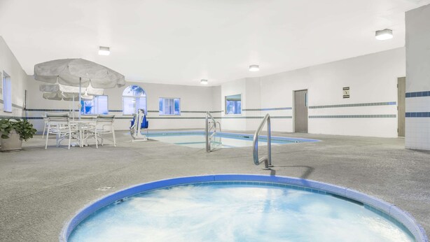 Piscina interior com água cristalina, prancha de mergulho e área de estar com guarda-sóis.