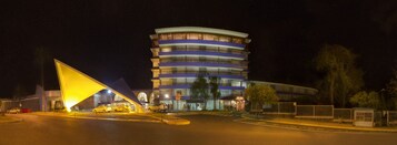 Um hotel moderno com fachada curva, vários andares e entrada bem iluminada.