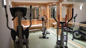 Uma academia com diversos equipamentos de exercícios, um espelho e um banco de madeira.