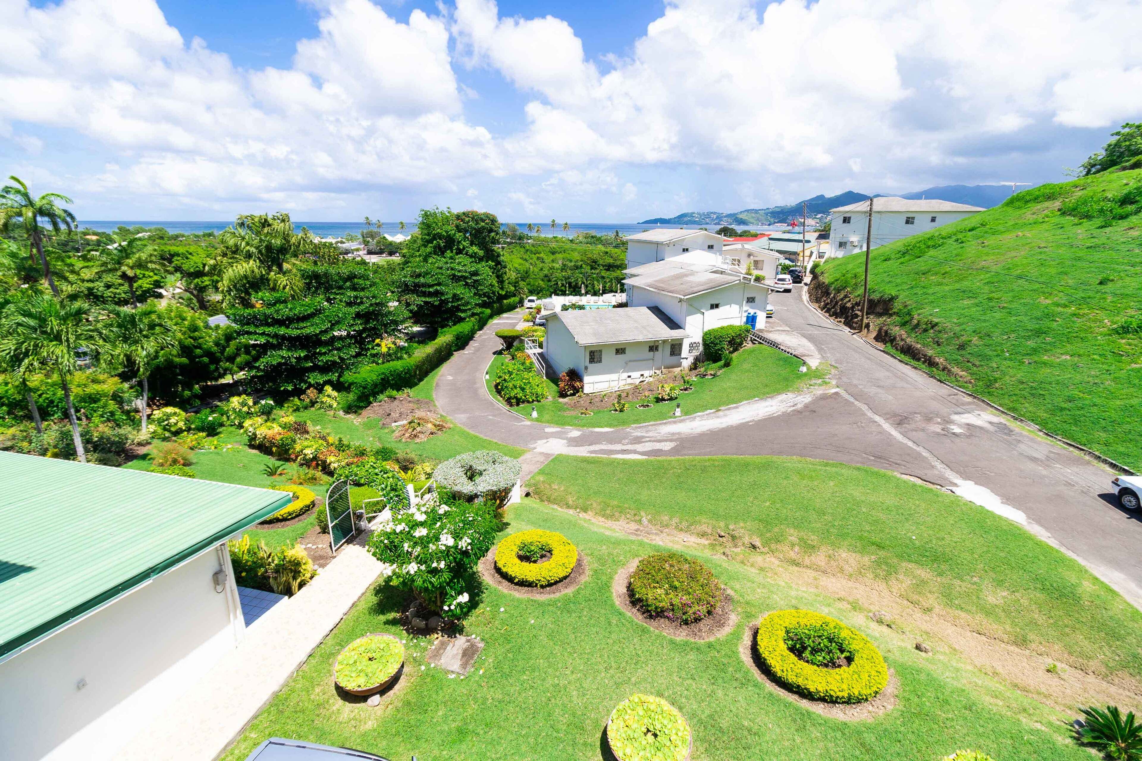 Um bairro residencial com casas, uma estrada sinuosa e vista para o oceano.