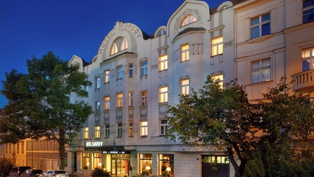 Um hotel de vários andares com estilo arquitetônico clássico, destacando uma entrada em arco e diversas janelas.