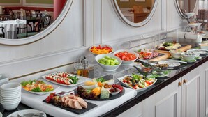 Buffet com diversos pratos, incluindo saladas, carnes e queijos.