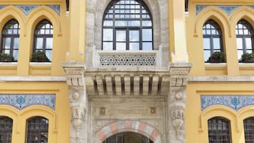 Um edifício com uma entrada central em arco, várias janelas e uma varanda com detalhes decorativos.