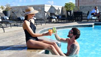 Área de piscina com espreguiçadeiras e um muro de pedra.