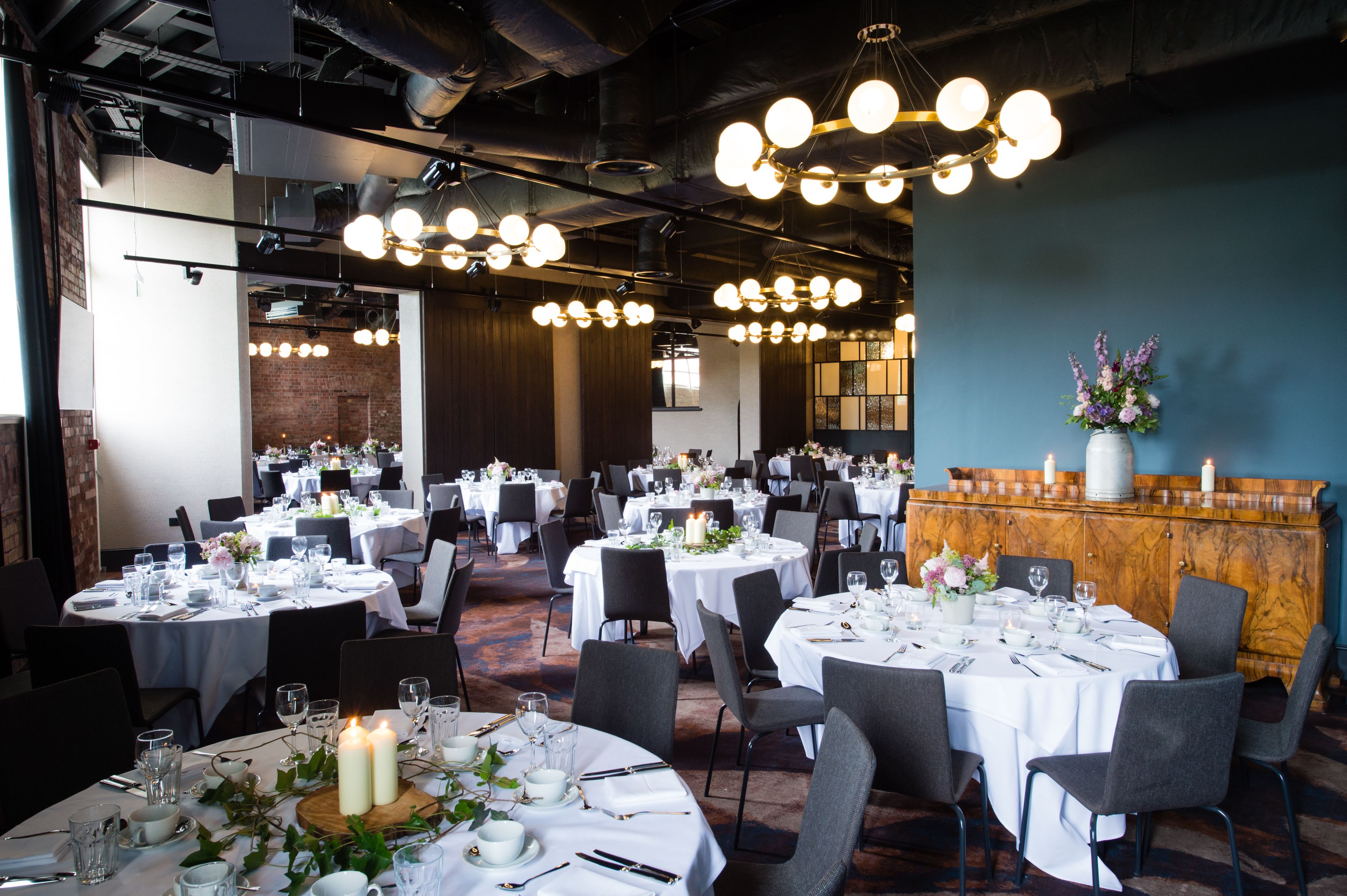 Restaurante com mesas redondas preparadas para refeições, com toalhas brancas e centros de mesa com velas.