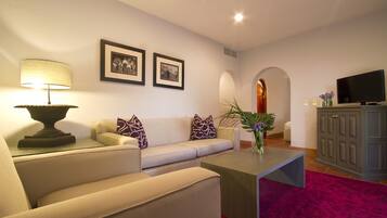 Sala de estar com sofá, mesa de centro, abajur, quadros nas paredes, televisão e aparador.