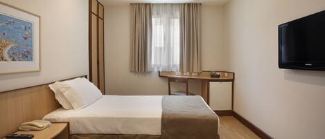 Quarto de hotel com duas camas, uma escrivaninha, uma televisão e um quadro na parede.