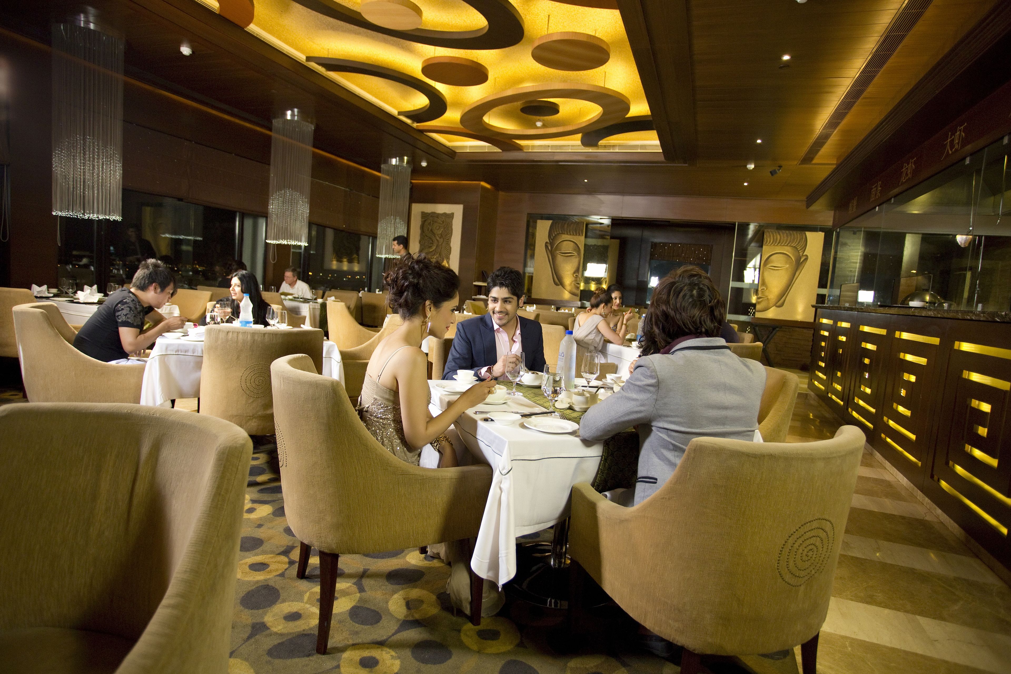 Restaurante com mesas e cadeiras redondas, piso estampado e design moderno no teto.