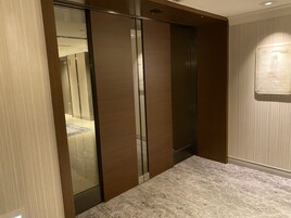Um elevador moderno com porta de vidro e interior em madeira.